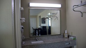 Casa de banho com lavatório, espelho, porta-toalhas e barra de apoio.