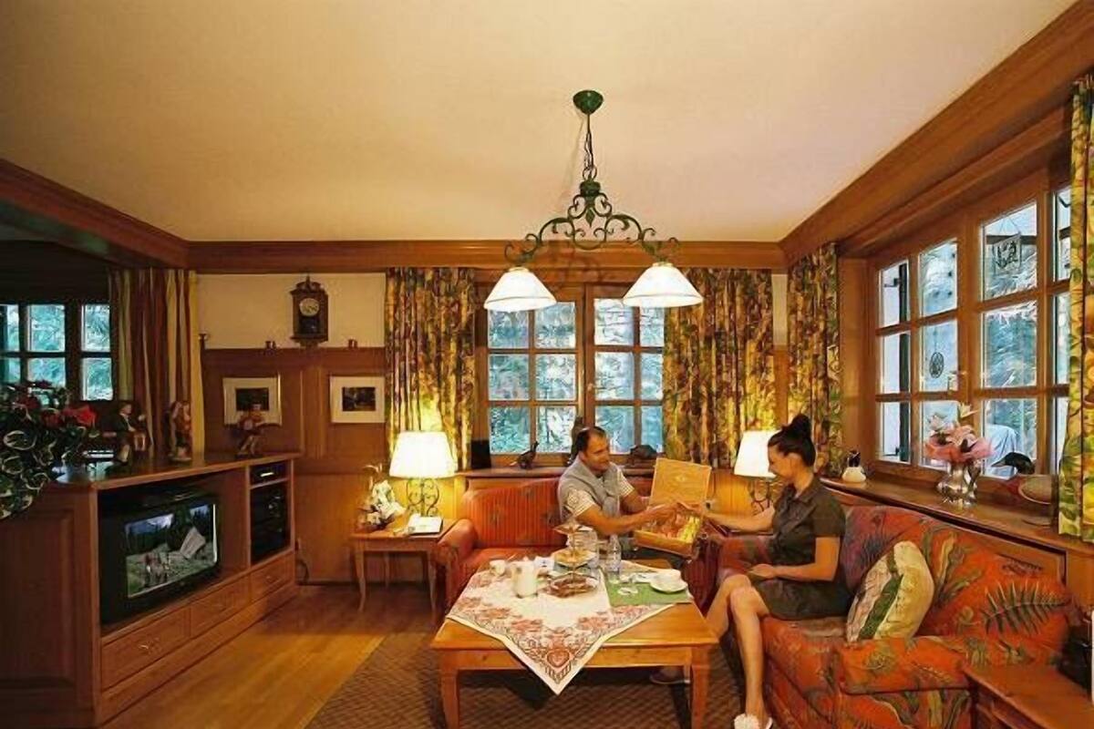 Uma sala de estar aconchegante com uma mesa de madeira, dois sofás e uma televisão.