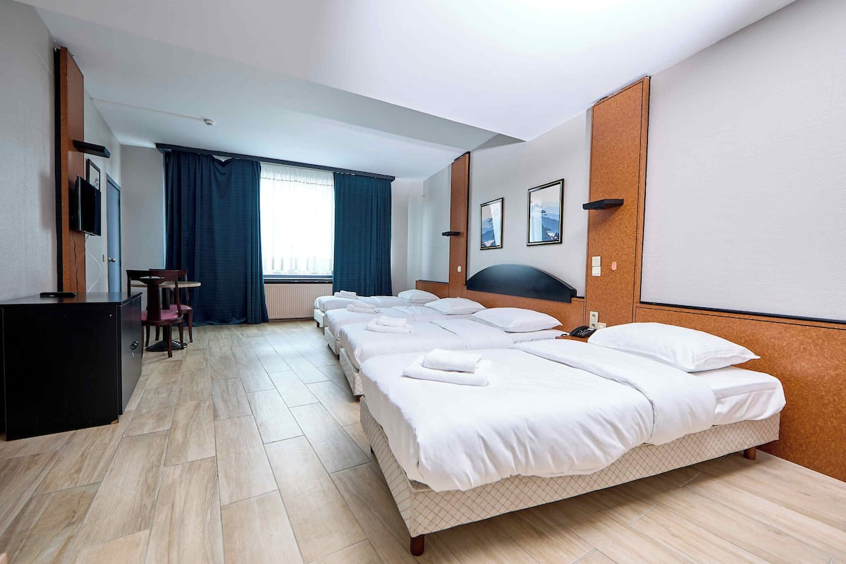 Quarto de hotel com uma cama grande, uma escrivaninha, uma cadeira e uma televisão.