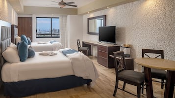 Quarto de hotel com cama, escrivaninha, televisão e vista para a cidade.
