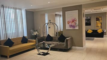 Uma sala de estar moderna com um sofá, uma mesa de centro de vidro e uma escultura de metal decorativa.