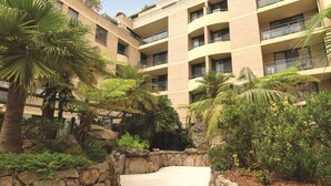 Um hotel com vários andares, varandas, paredes de pedra e plantas tropicais.