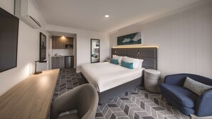 Quarto de hotel com cama, escrivaninha, cadeira, sofá e mesinha redonda.