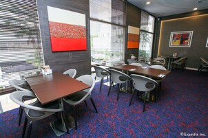 Uma sala de conferências com carpete azul, cadeiras brancas e uma mesa castanha.