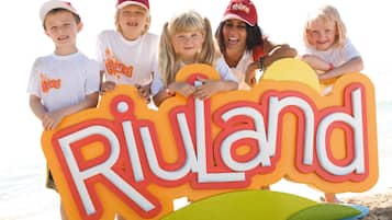 Um grupo de pessoas segurando uma placa com a inscrição 'Riuland' numa praia.