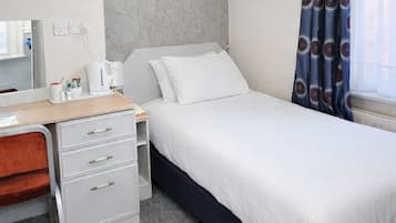 Quarto de hotel com cama, escrivaninha e cadeira.