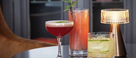 Três bebidas sobre uma mesa com um abajur.