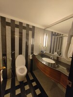 Casa de banho moderna com sanita, lavatório e espelho.
