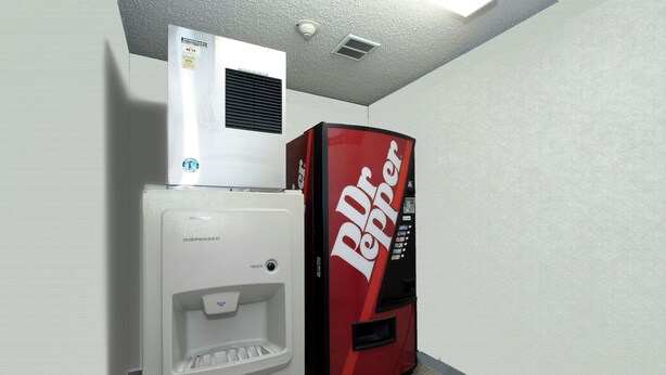 Uma máquina de vendas automática e uma pequena geladeira num canto.