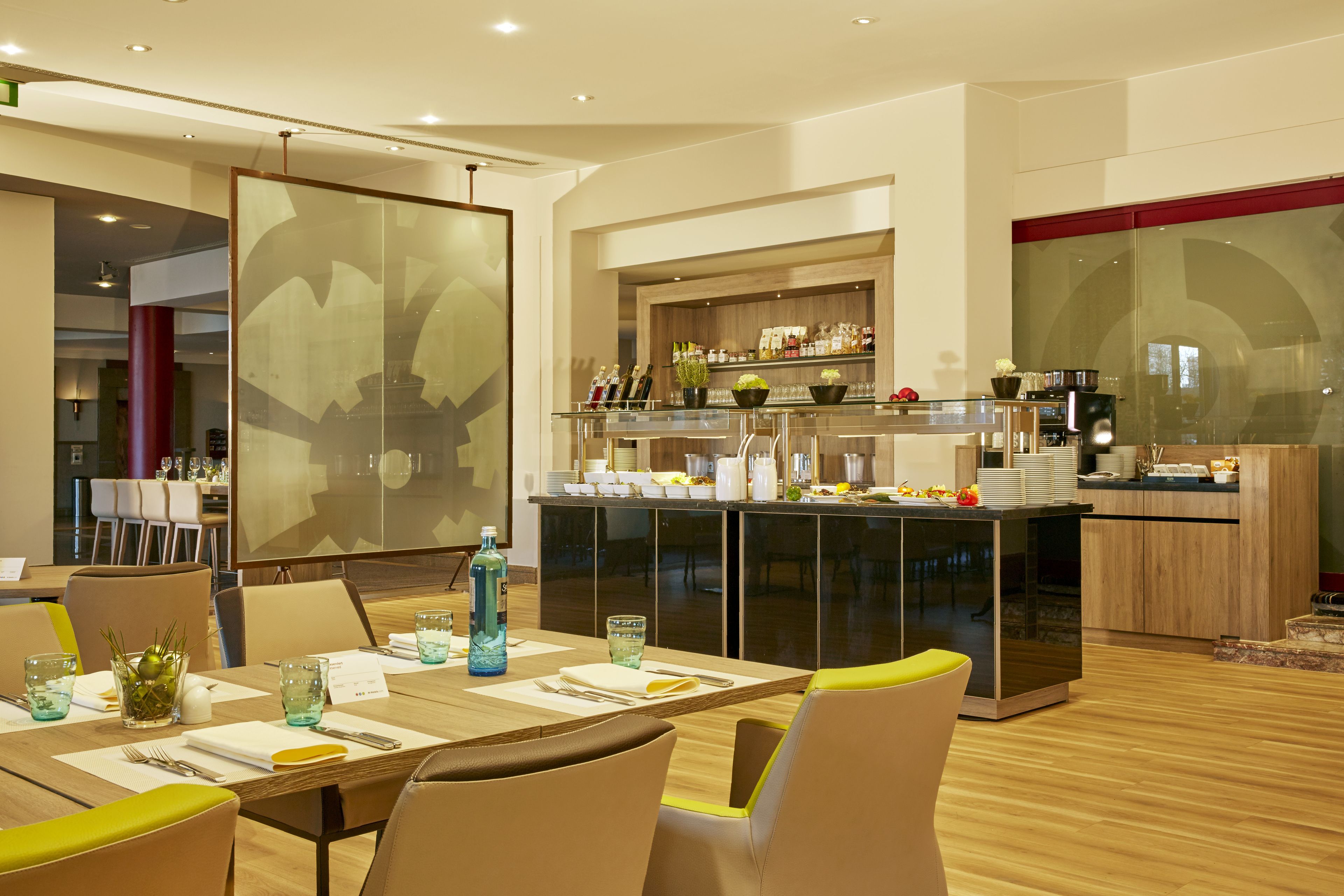 Uma área de jantar moderna com uma mesa de madeira, cadeiras e uma cozinha ao fundo.