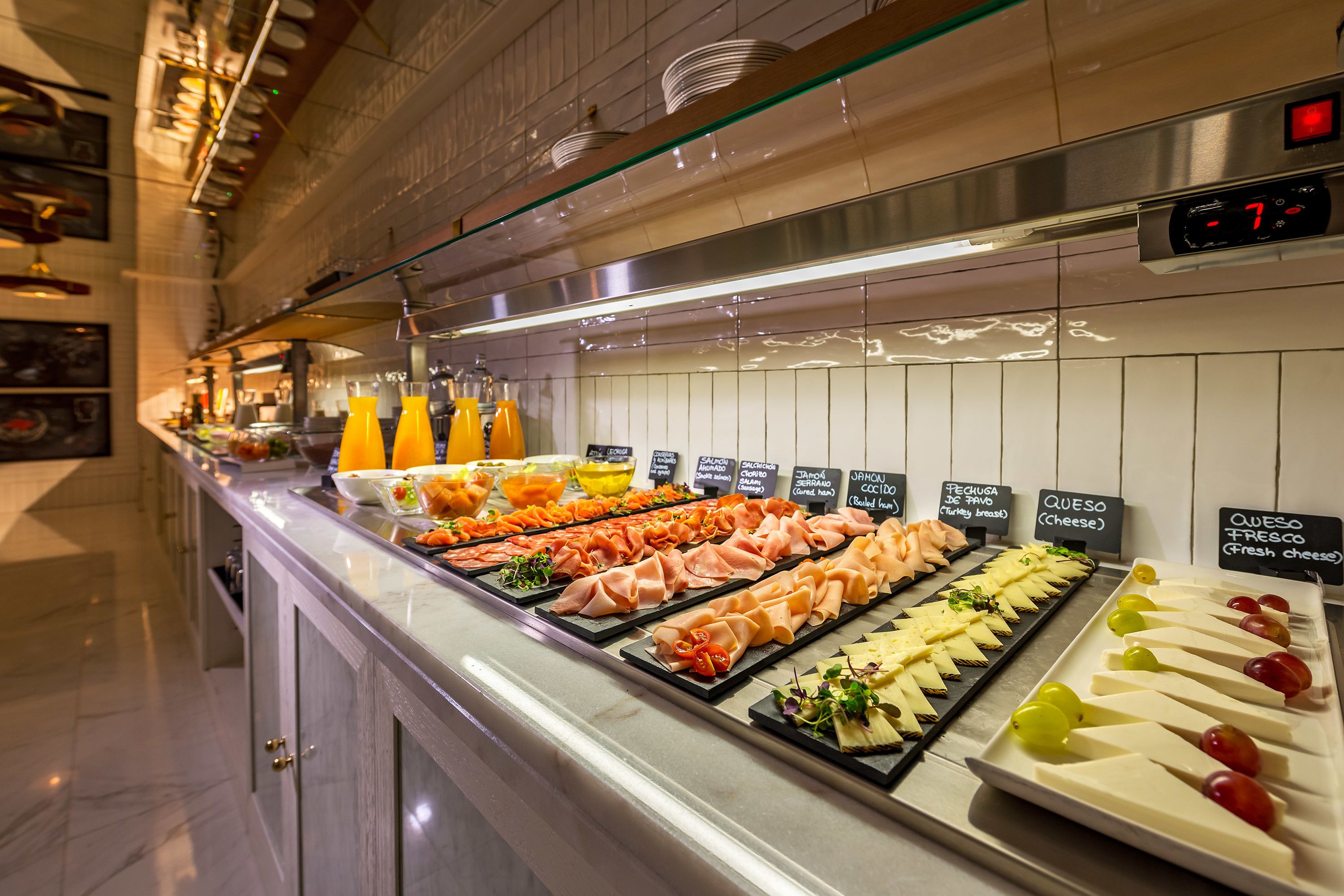 Buffet com diversas opções de comida, incluindo carnes, queijos e frutas.
