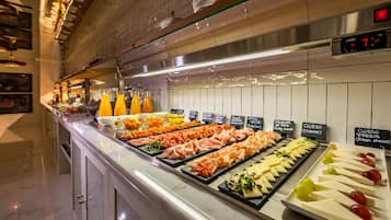 Buffet com diversas opções de comida, incluindo carnes, queijos e frutas.