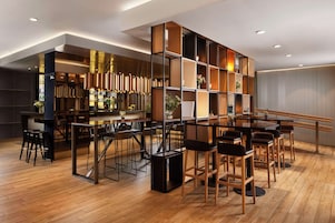 Uma área de bar moderna com vários bancos e balcão, com mobiliário de madeira e metal.