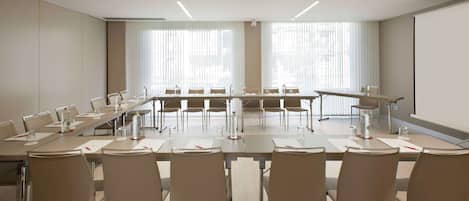 Uma sala de conferências com uma mesa comprida, cadeiras e uma tela de projetor.