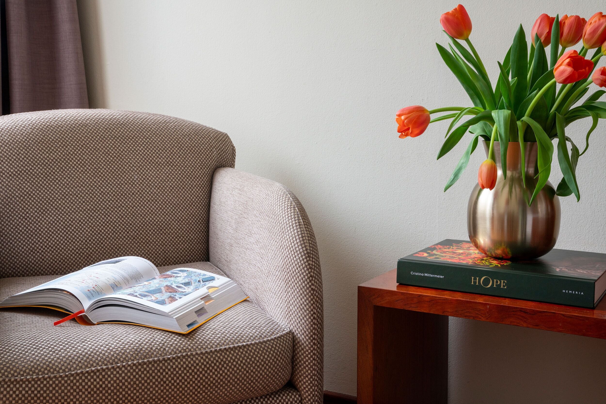 Um livro com o título 'HOPE' sobre uma mesa de madeira ao lado de uma cadeira com uma revista aberta.
