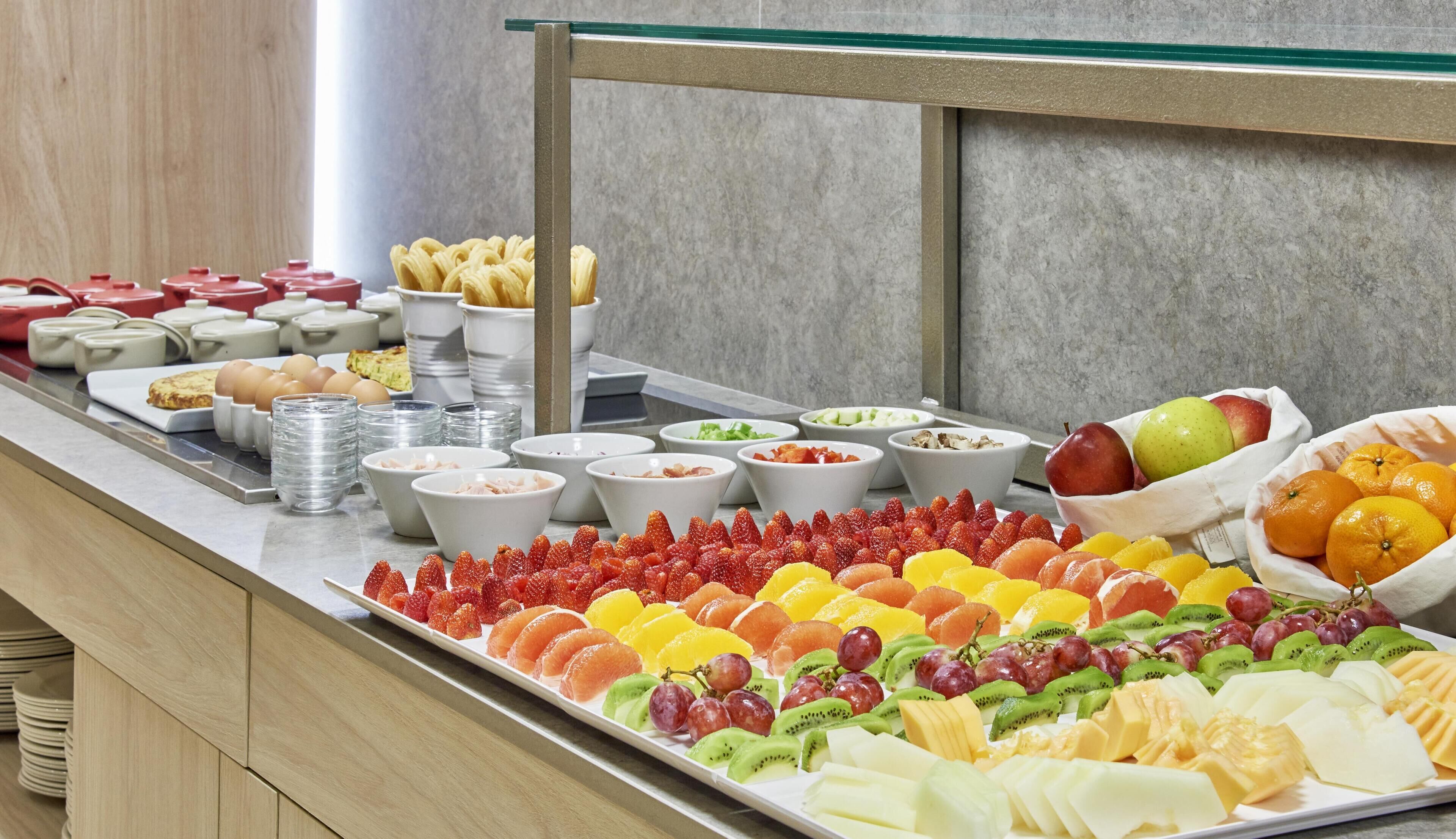 Buffet com frutas, queijos e outros alimentos.