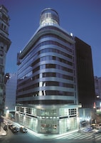 Um hotel moderno com fachada curva, janelas amplas e um letreiro grande no terraço.