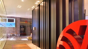 Um hall de hotel moderno com uma recepção, área de estar e uma grande escultura abstrata vermelha.