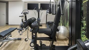 Uma academia com diversos equipamentos de exercícios, incluindo um banco, elíptico e aparelho de musculação.