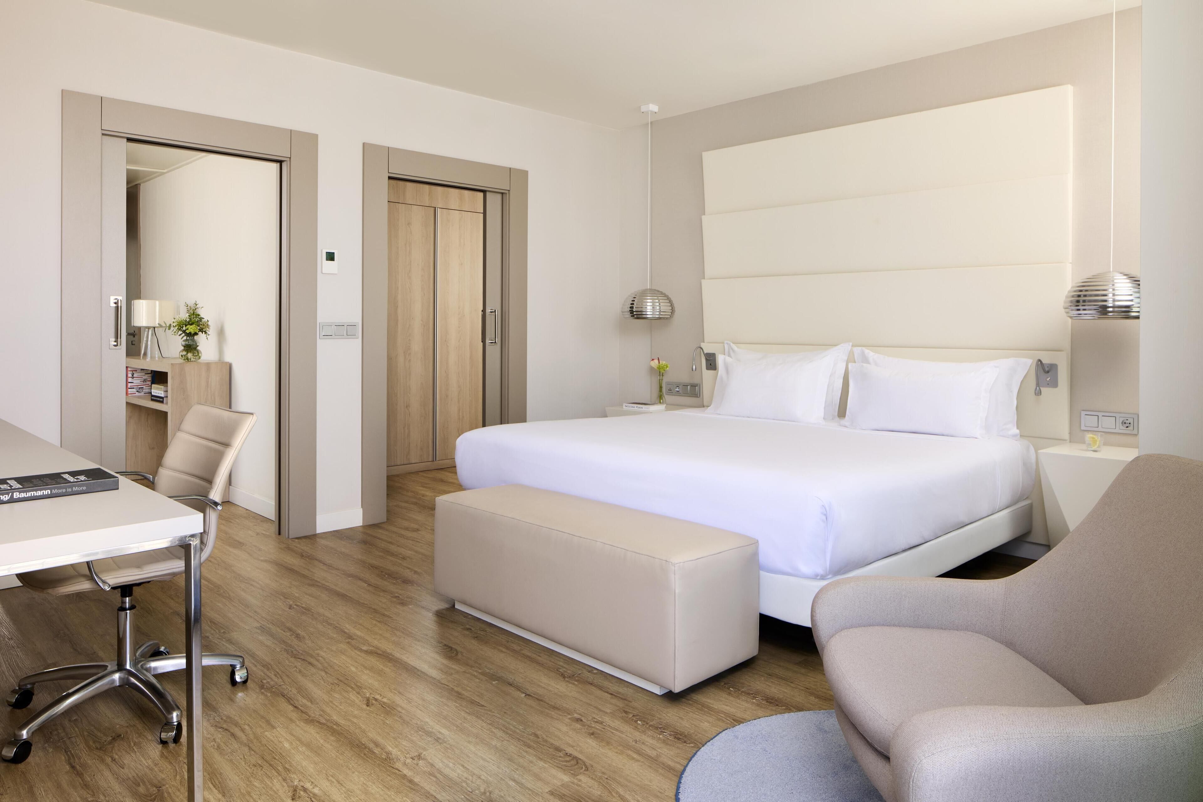 Quarto de hotel moderno com uma cama grande, uma escrivaninha e uma cadeira.