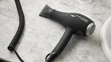 Um secador de cabelo preto com fio flexível sobre uma bancada de mármore.