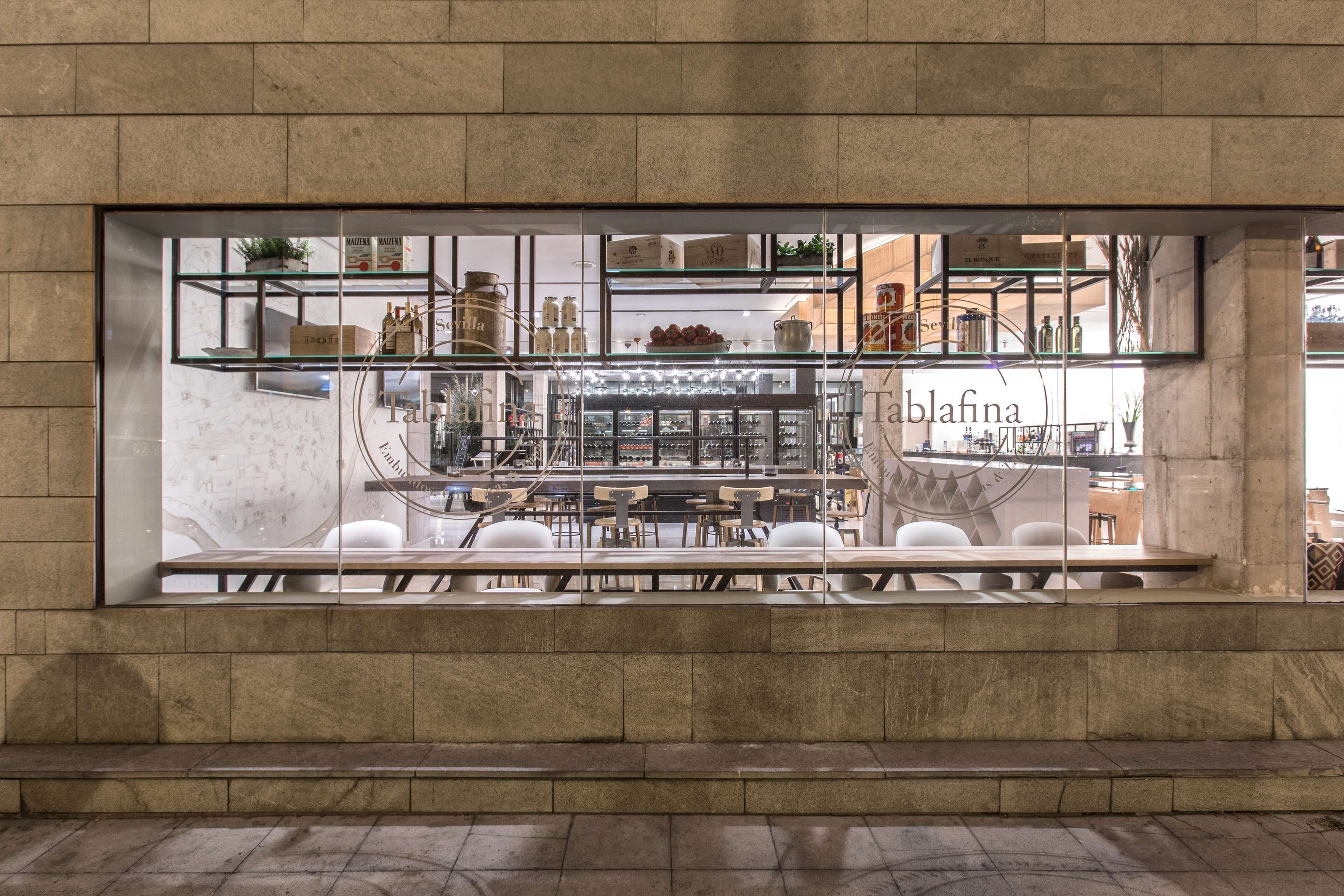 Um interior moderno com área de bar, assentos e um quadro de menu visível.