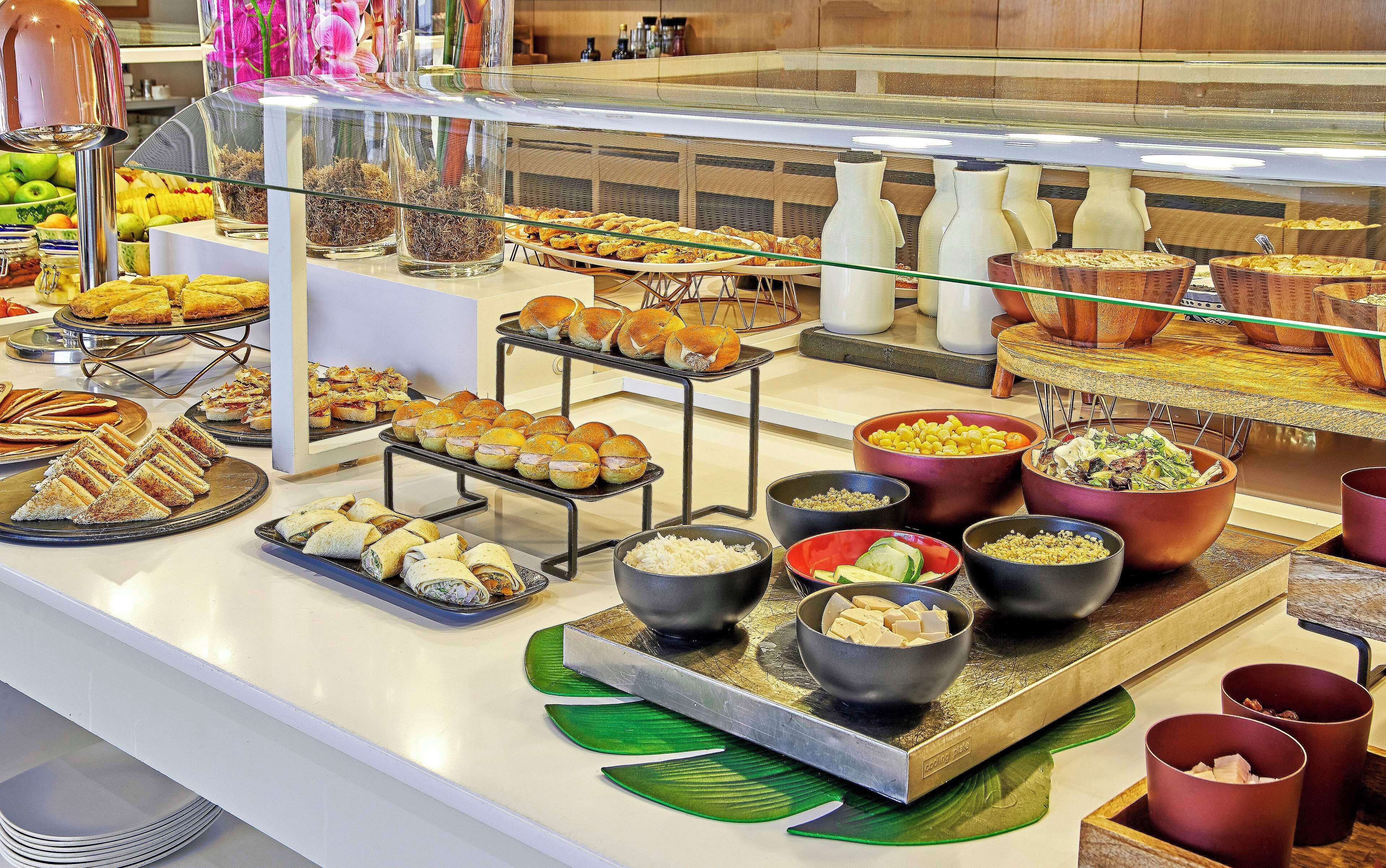 Buffet com diversas opções de comida, incluindo sanduíches, saladas e sobremesas.