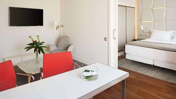 Quarto de hotel moderno com área de refeições, cama e televisão.