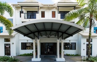 Um edifício moderno com entrada coberta, colunas e fachada simétrica.