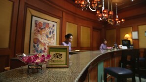 Uma área de recepção com uma taça de vidro cheia de frutas, uma placa emoldurada do TripAdvisor e um candelabro.