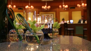 Uma área de bar com vários pequenos vasos de vidro contendo flores e velas, apoiada sobre um balcão de granito.
