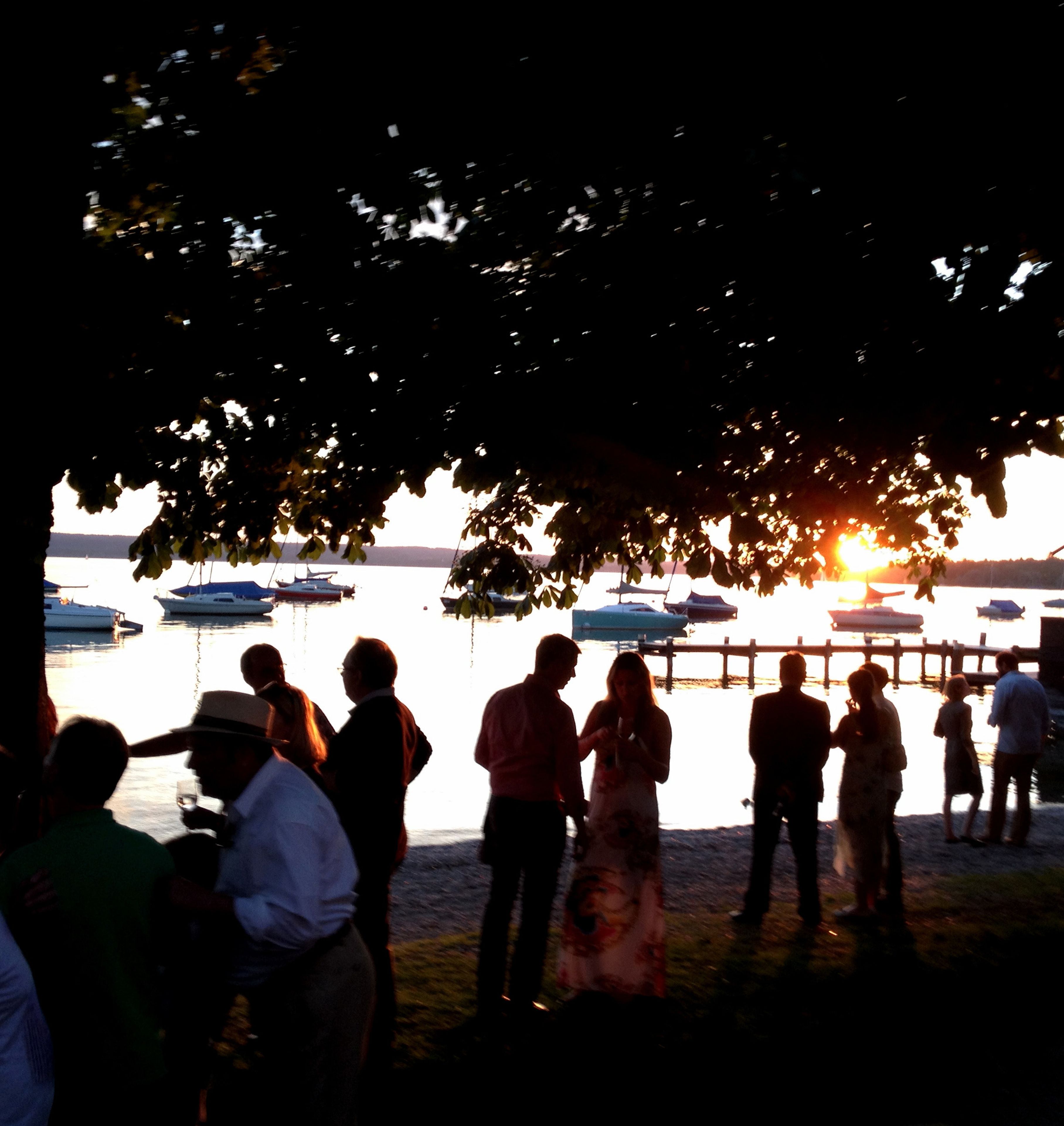 Um grupo de pessoas à beira-mar ao pôr do sol.