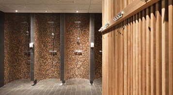 Um banheiro moderno com paredes em mosaico, painel de madeira e piso ladrilhado.