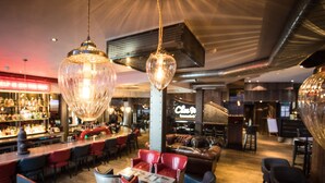 Uma área de bar com assentos, lustres de cristal pendurados e uma placa visível com o nome 'Chloe's'.