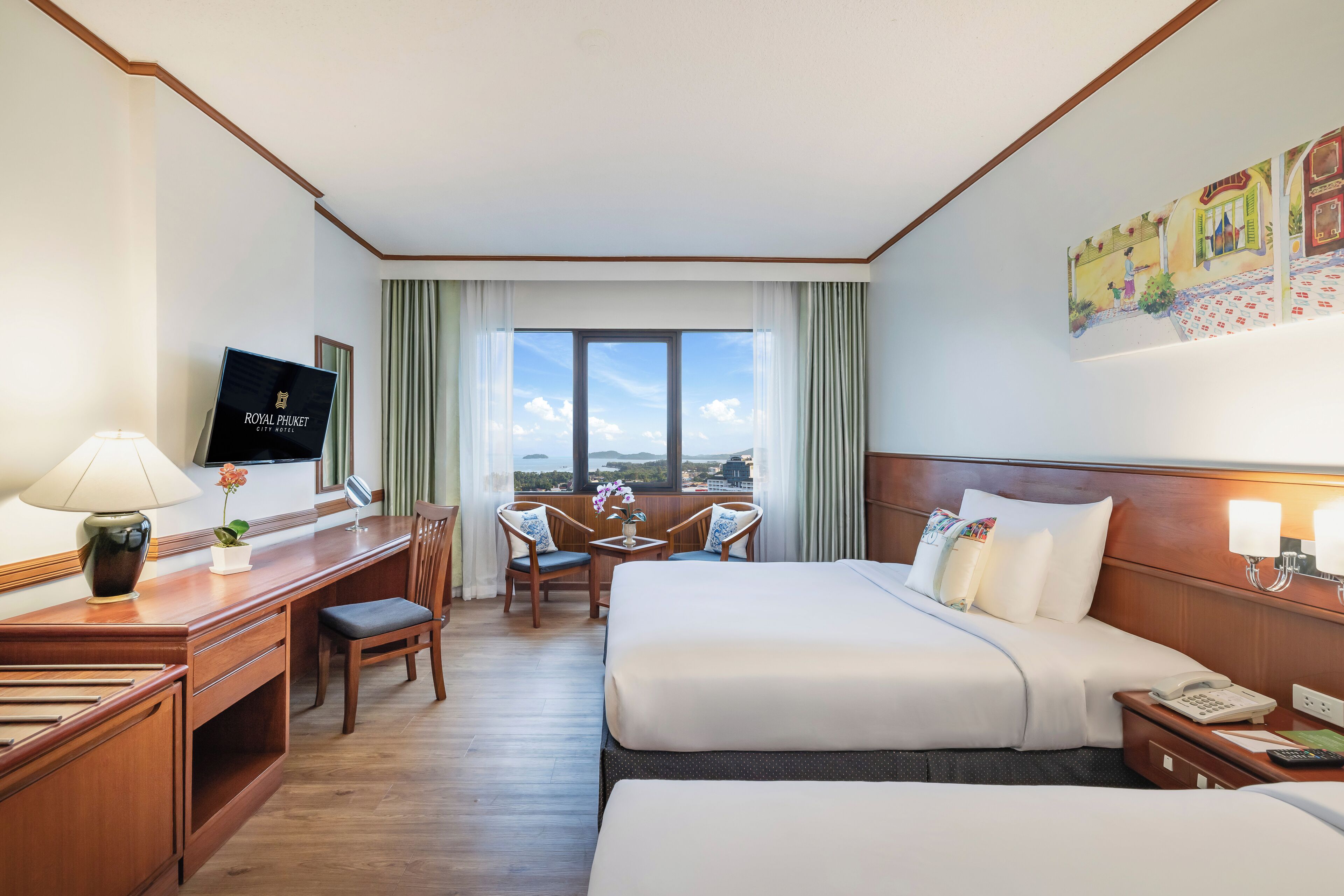 Quarto de hotel com cama, escrivaninha, cadeira, televisão e janela com vista.