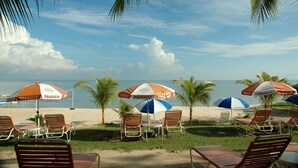 Um espaço de relaxamento à beira-mar, com vários guarda-sóis e cadeiras, com vista para o oceano.