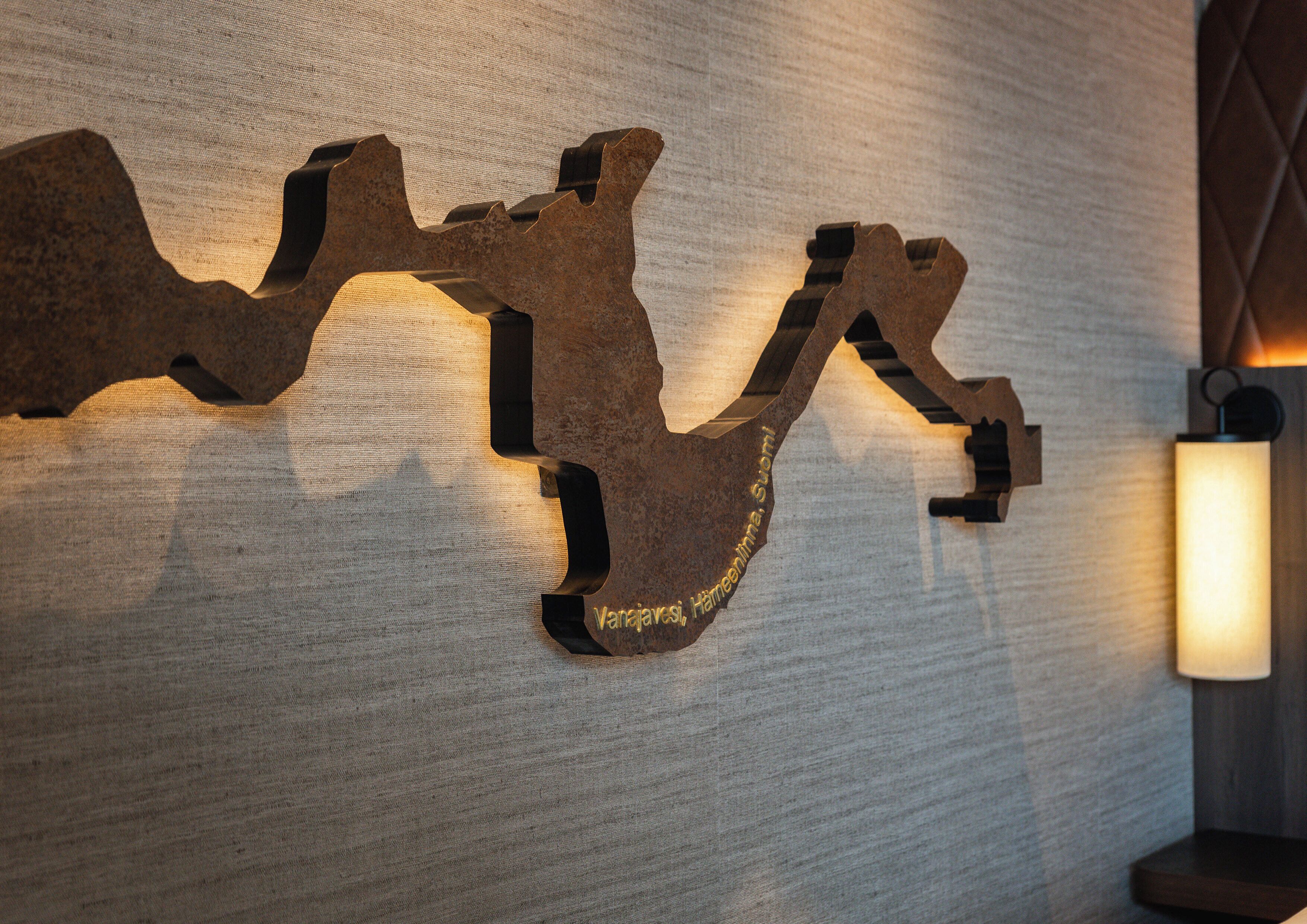 Escultura de metal fixada na parede com inscrições.