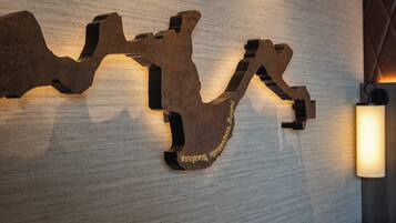 Escultura de metal fixada na parede com inscrições.