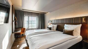 Quarto de hotel com uma cama grande, uma mesa e uma cadeira.