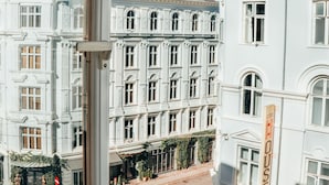 Vista de uma rua com edifícios, um carro branco e bicicletas.