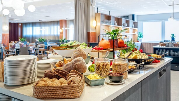 Disposição de buffet com diversos alimentos, pratos e utensílios.