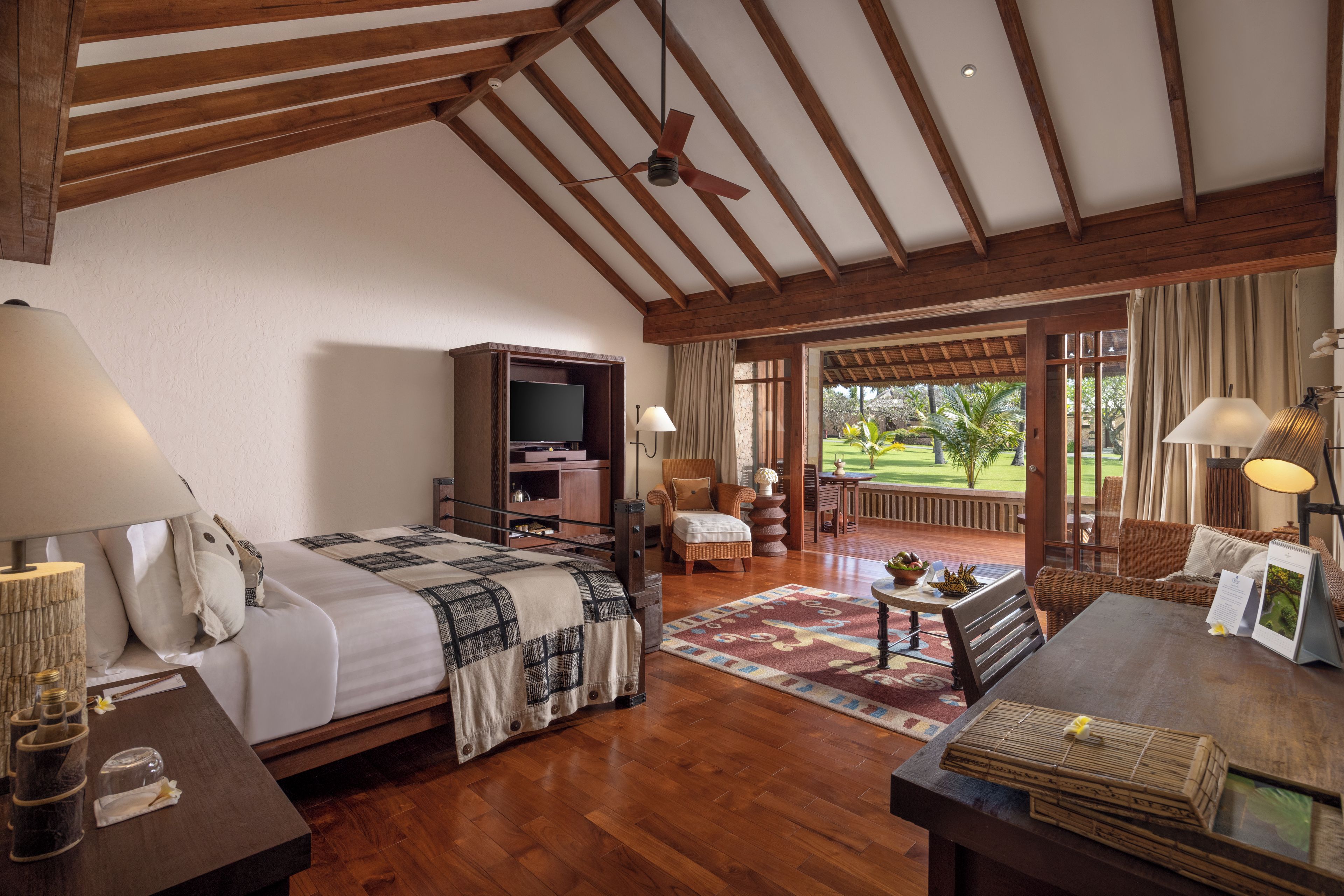 Quarto espaçoso com cama, escrivaninha, cadeira e televisão. Possui uma varanda com vista para o jardim.