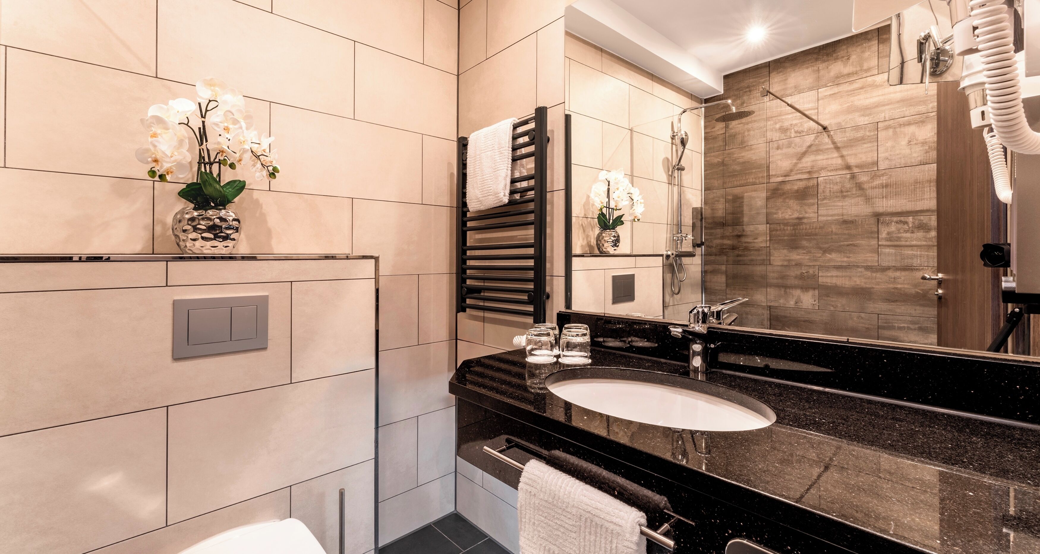 Casa de banho moderna com lavatório de bancada preta, espelho e porta-toalhas.