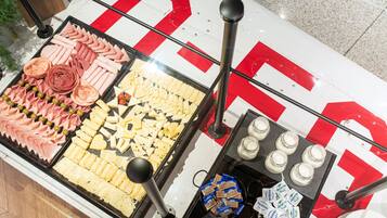 Exposição de alimentos com diversos queijos, carnes e acompanhamentos.