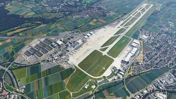 Vista aérea de um aeroporto com várias pistas, rodeado por campos agrícolas e áreas residenciais.