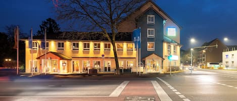 Um hotel com vários andares, entrada no nível da rua, ciclovia e faixa de pedestres.