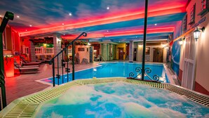 Piscina com hidromassagem, área de estar interna e teto colorido.