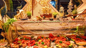Exposição de frutos do mar com diferentes tipos de marisco e elementos decorativos como uma maqueta de navio e lanternas.