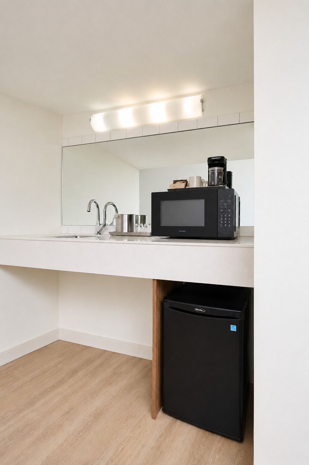 Uma cozinha compacta equipada com micro-ondas, cafeteira e lixeira.