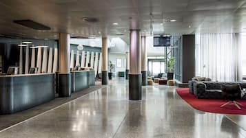 Um lobby moderno com balcão de recepção, área de estar e uma grande janela.